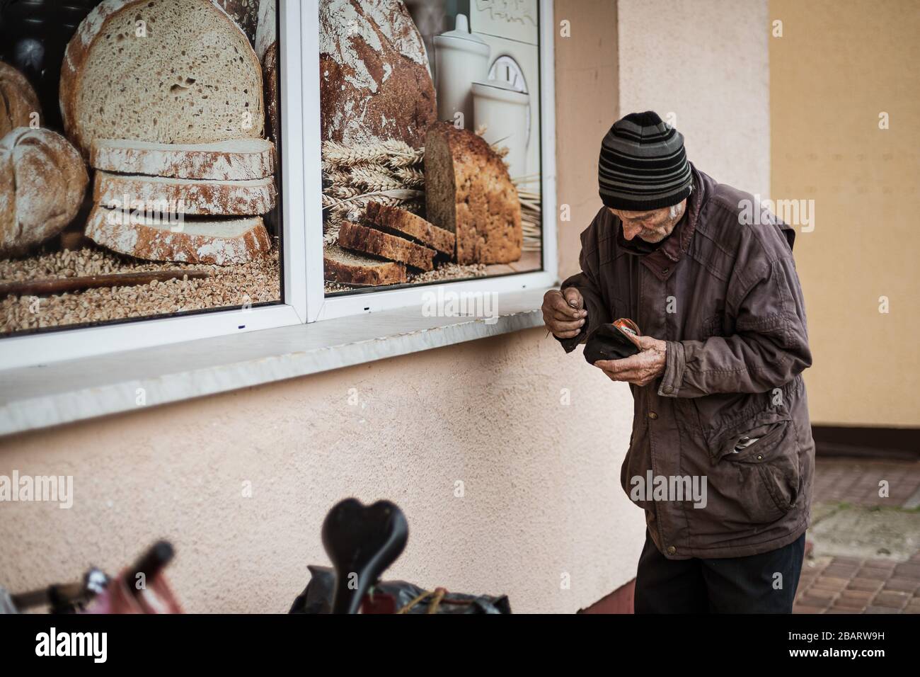 LUBIN, POLAND - MARCH 19, 2020. A poor old man pulls coins out of his ...