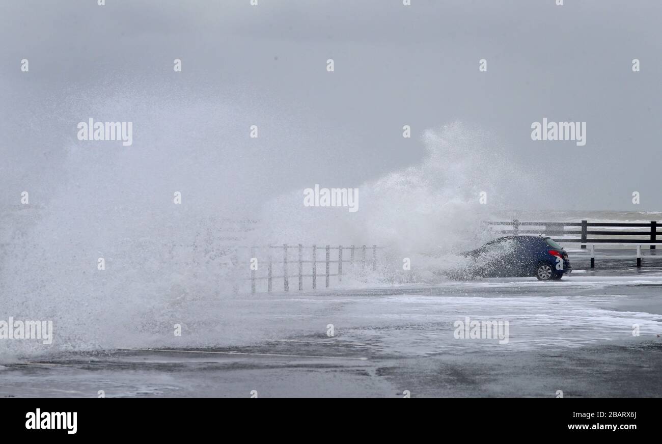 Waves crash over a car on the seafront during windy conditions in ...