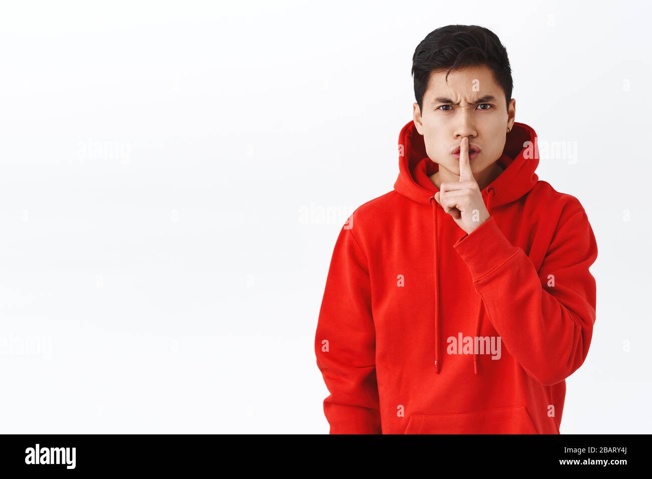 Portrait of angry, displeased asian hipster man in red hoodie, frowning ...