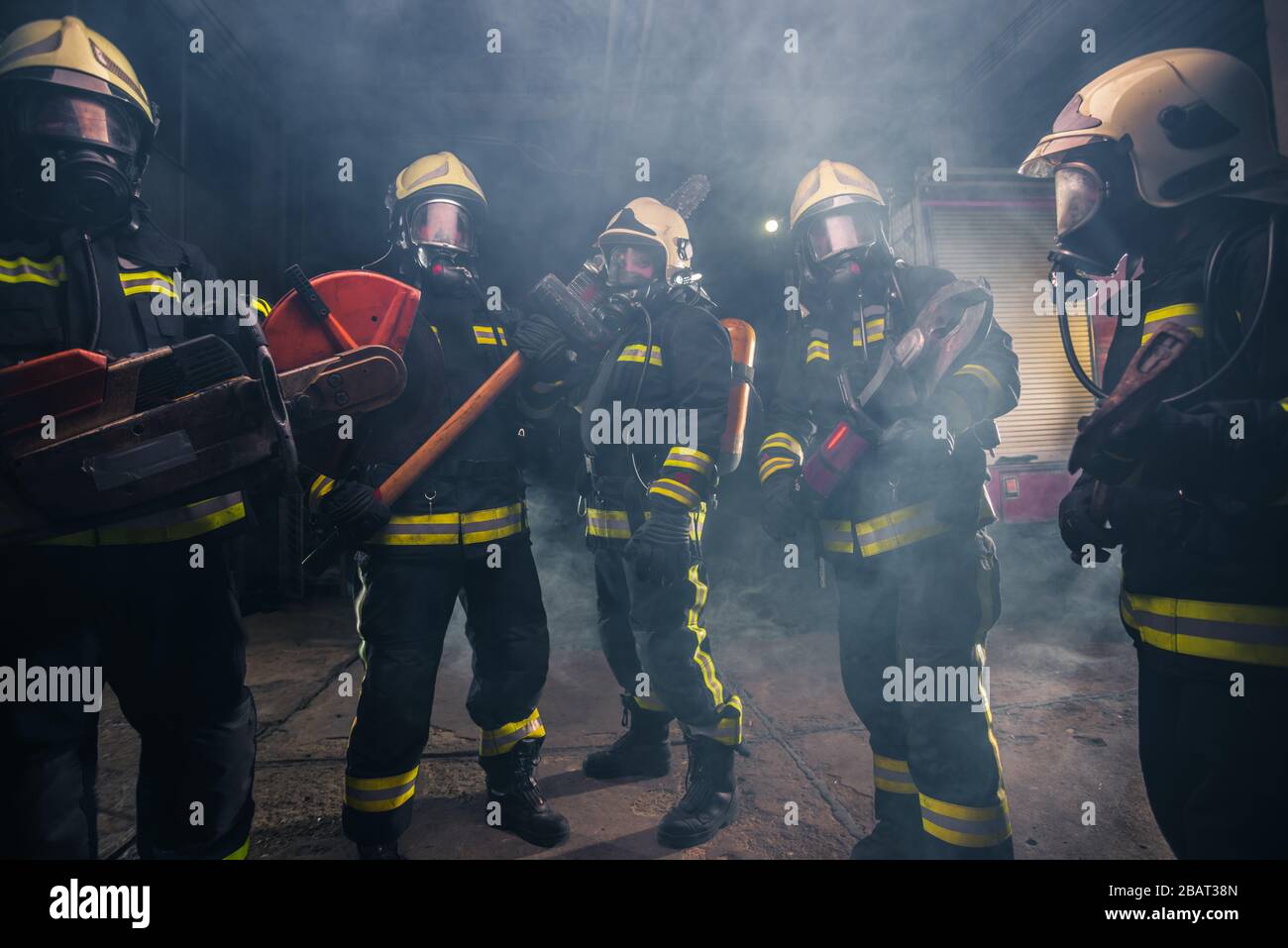 Group of firefighters with chainsaw and sledge hammer practicing in the ...