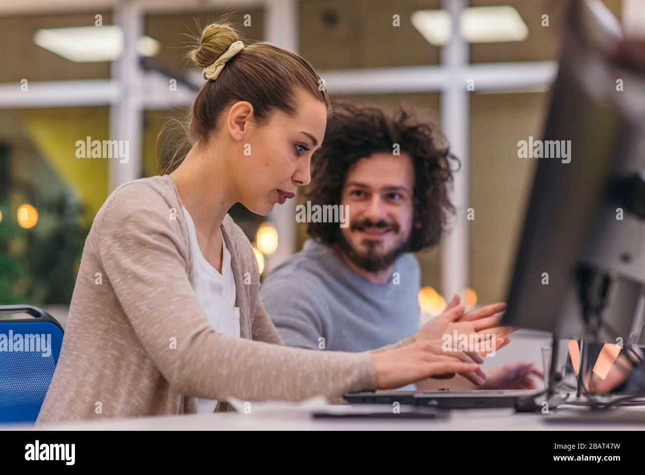 Two colleagues working on a project in modern startup offices. Guy with ...