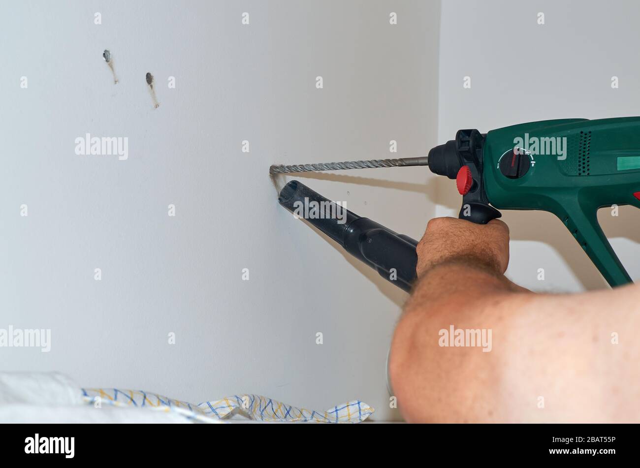 Drilling a hole in a concrete wall and vacuuming dust during the ...