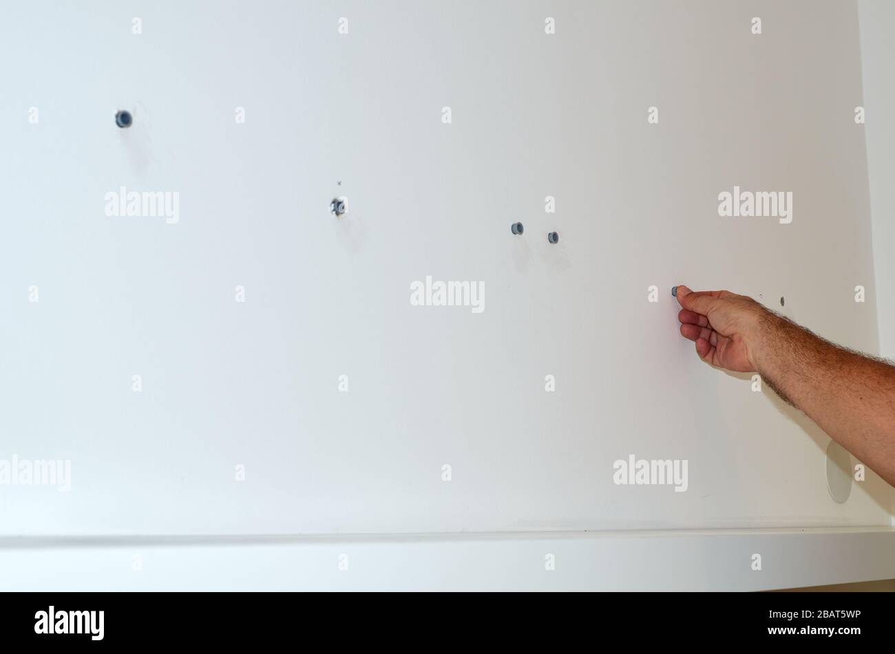 Inserting plastic screw plugs in a white wall Stock Photo - Alamy
