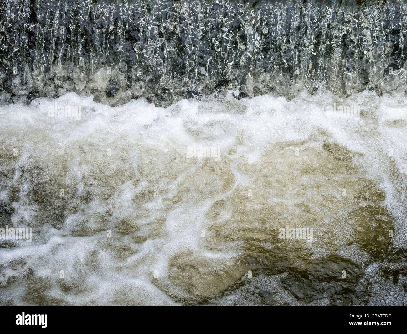 Water flowing in a small waterfall foaming and frothy Stock Photo - Alamy