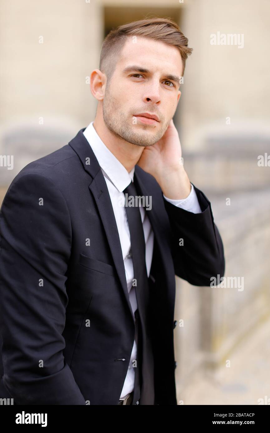 Portrait of young handsome man wearing black suit and leaning on ...