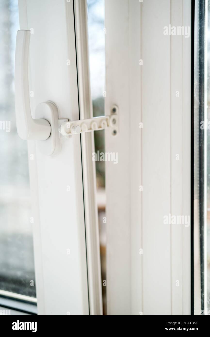 Open white PVC window with a fixing device for ventilation, in natural ...