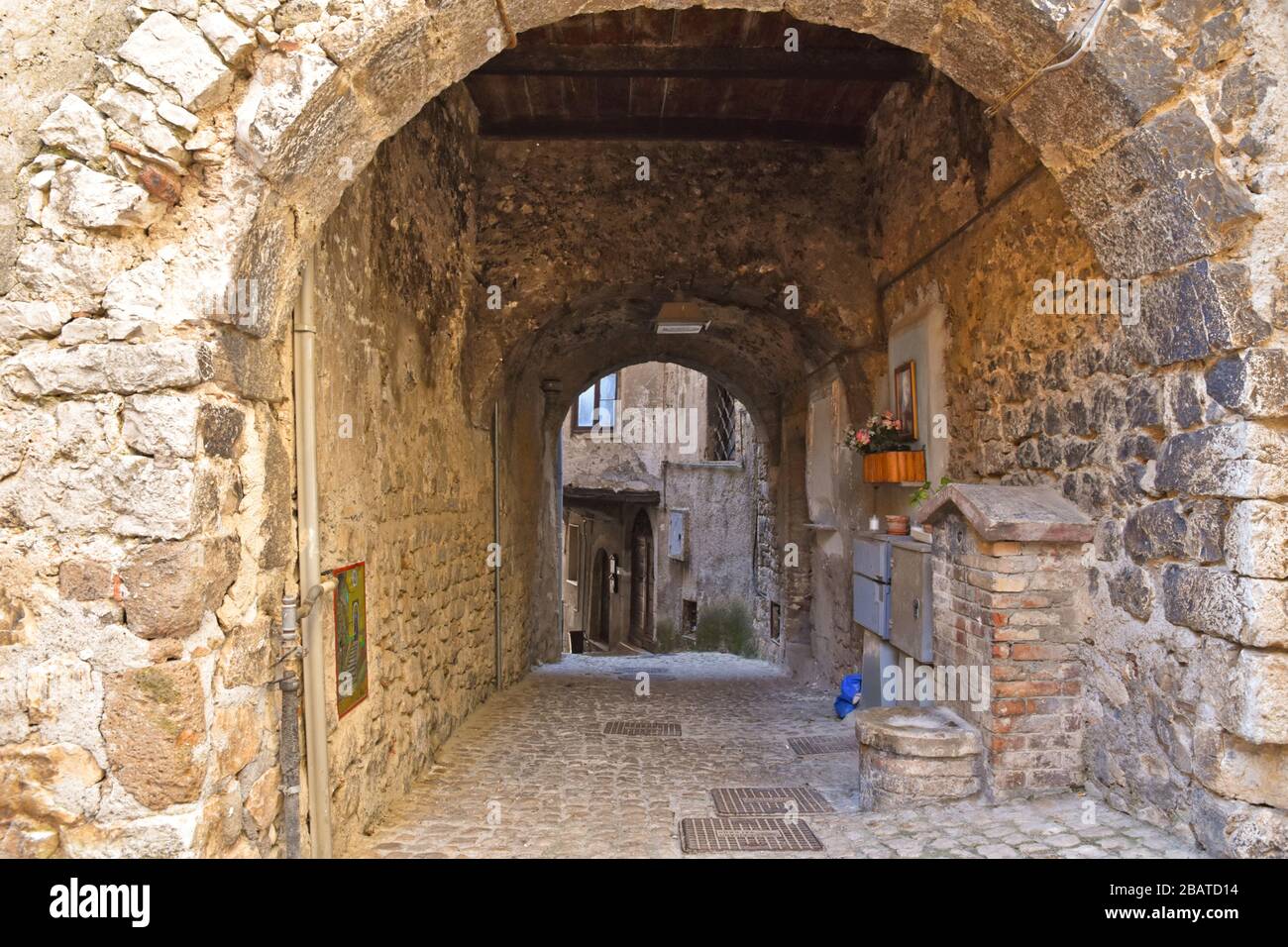 A narrow street between the stone houses of Prossedi, a medieval ...