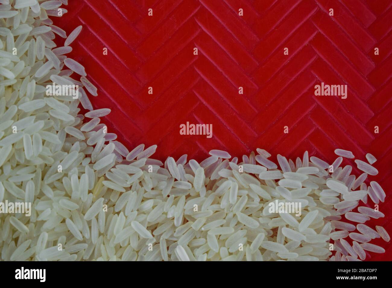 Grains of rice held in a designed red carpet where the rice grains are ...