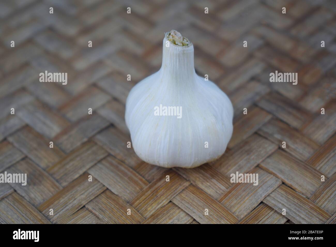 Portrait of a single garlic on top of an isolated wooden colored carpet ...