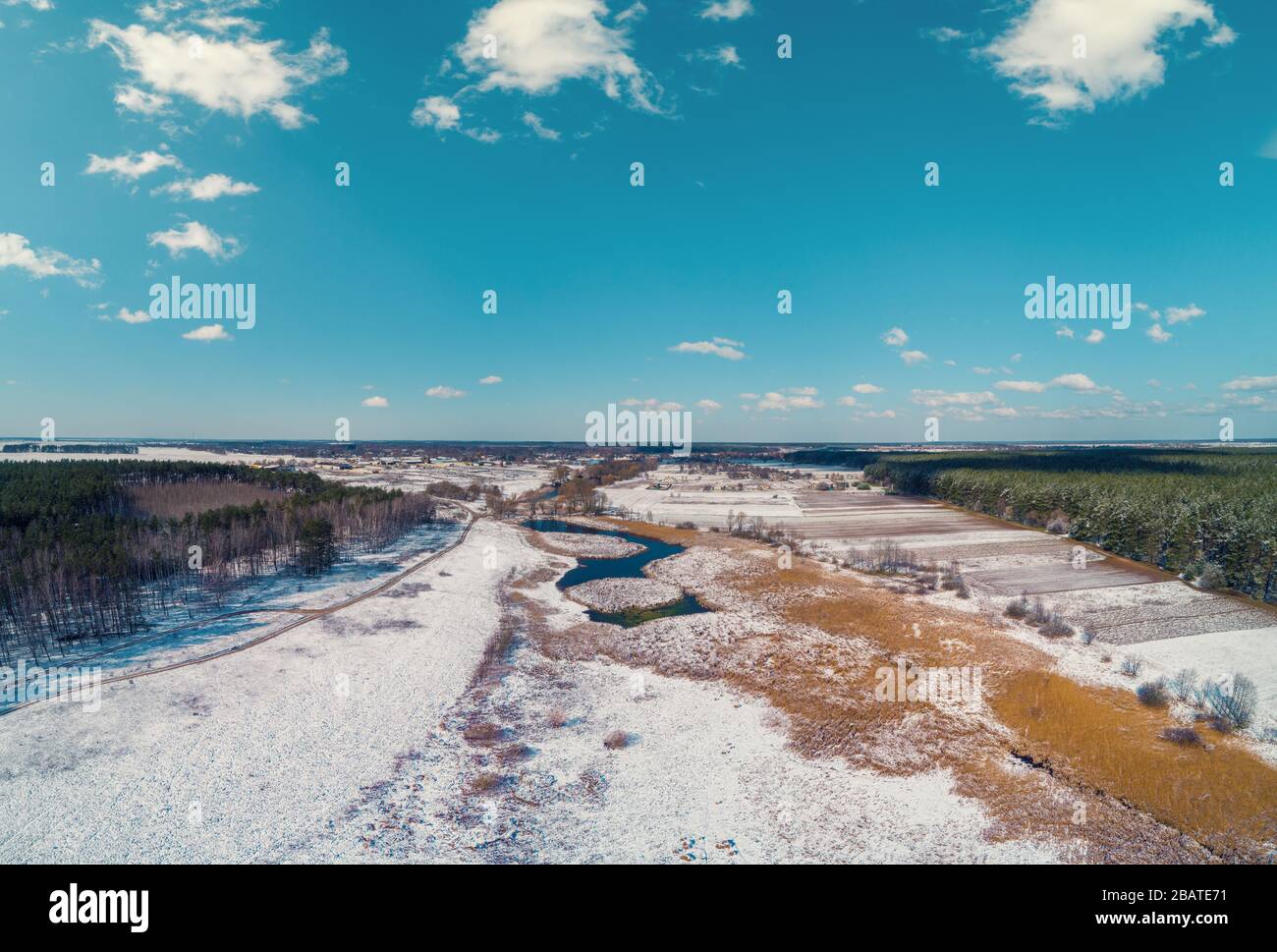 View from above of the countryside and brook on a sunny day. Snowy ...