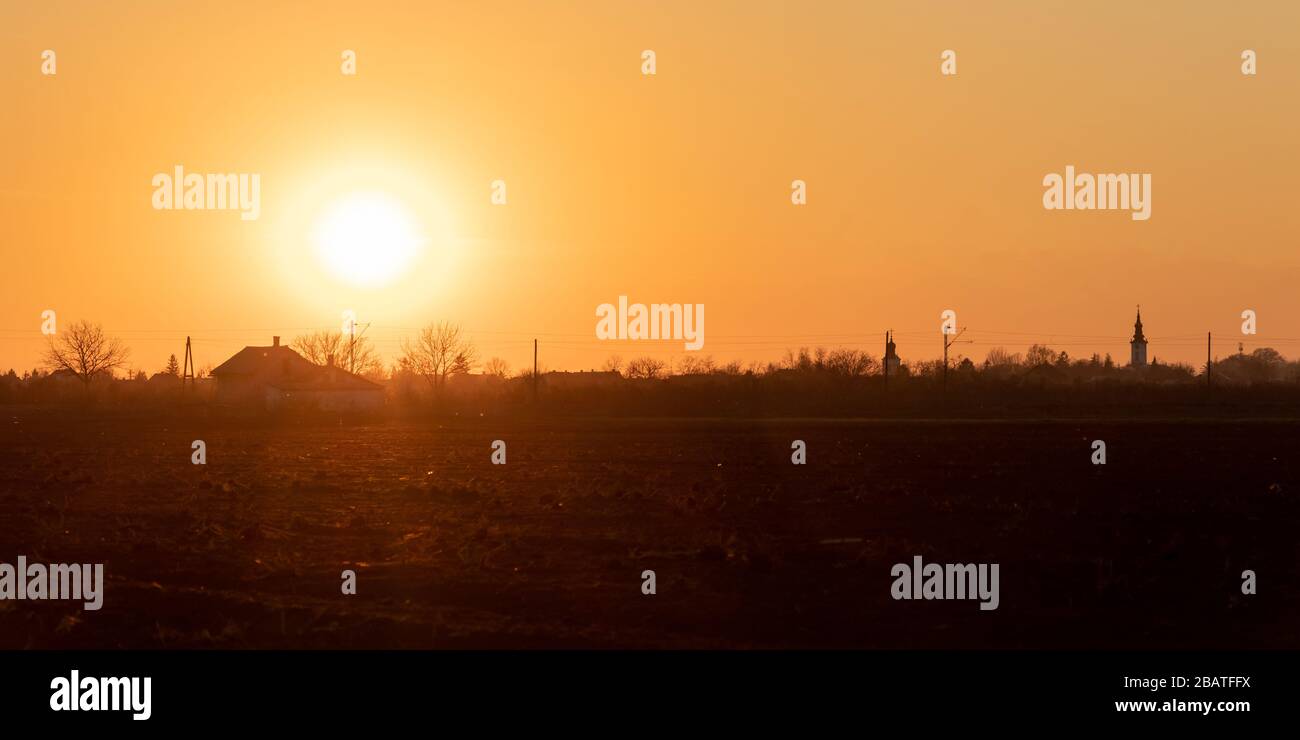 Sunset in rural area over the agricultural field. On distant blurred ...