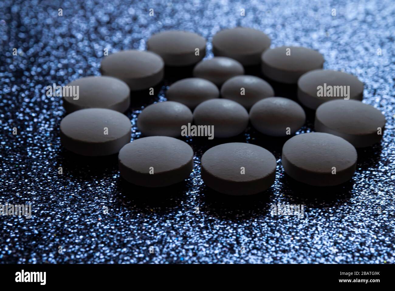 White pills, tablets capsule form a triangle in a circle on a dark ...