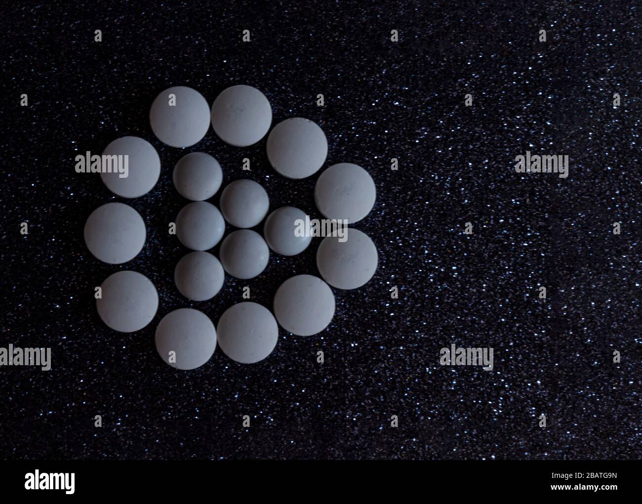 White pills, tablets capsule form a triangle in a circle on a dark ...