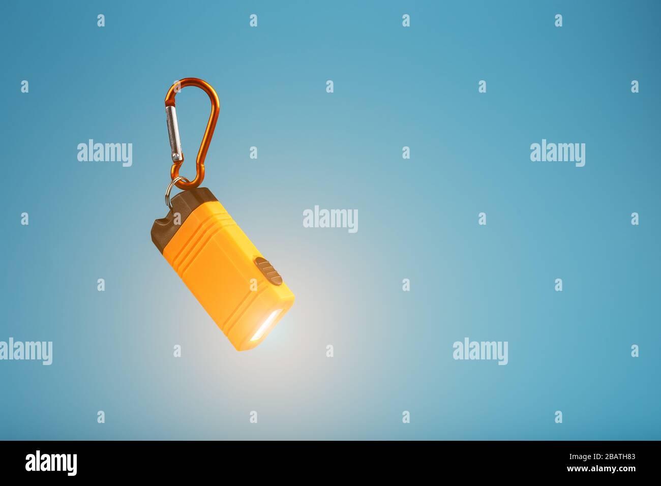 Orange led Flashlight with a carabiner on a blue background. LED lights ...