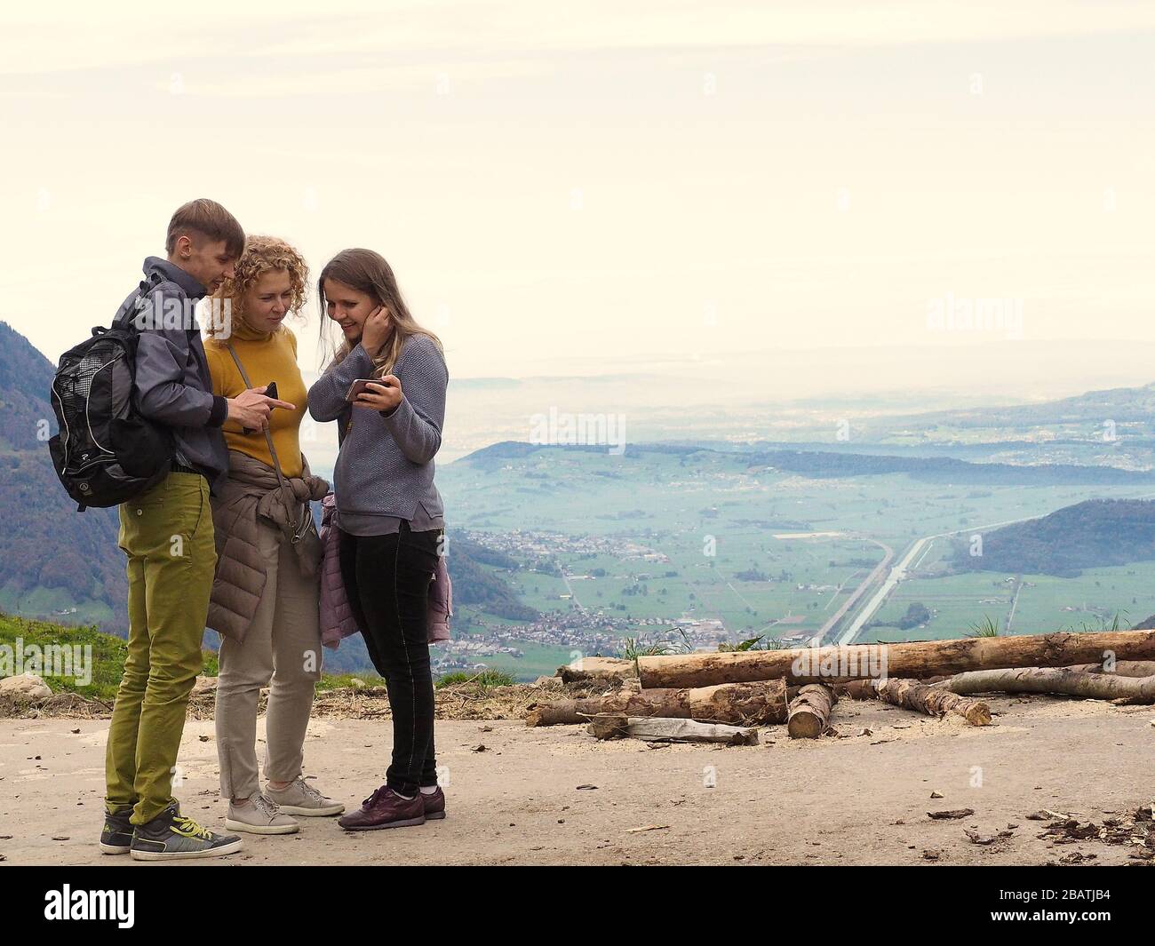 Young group of 3 upon a mountain standing together, shwoing and talking ...
