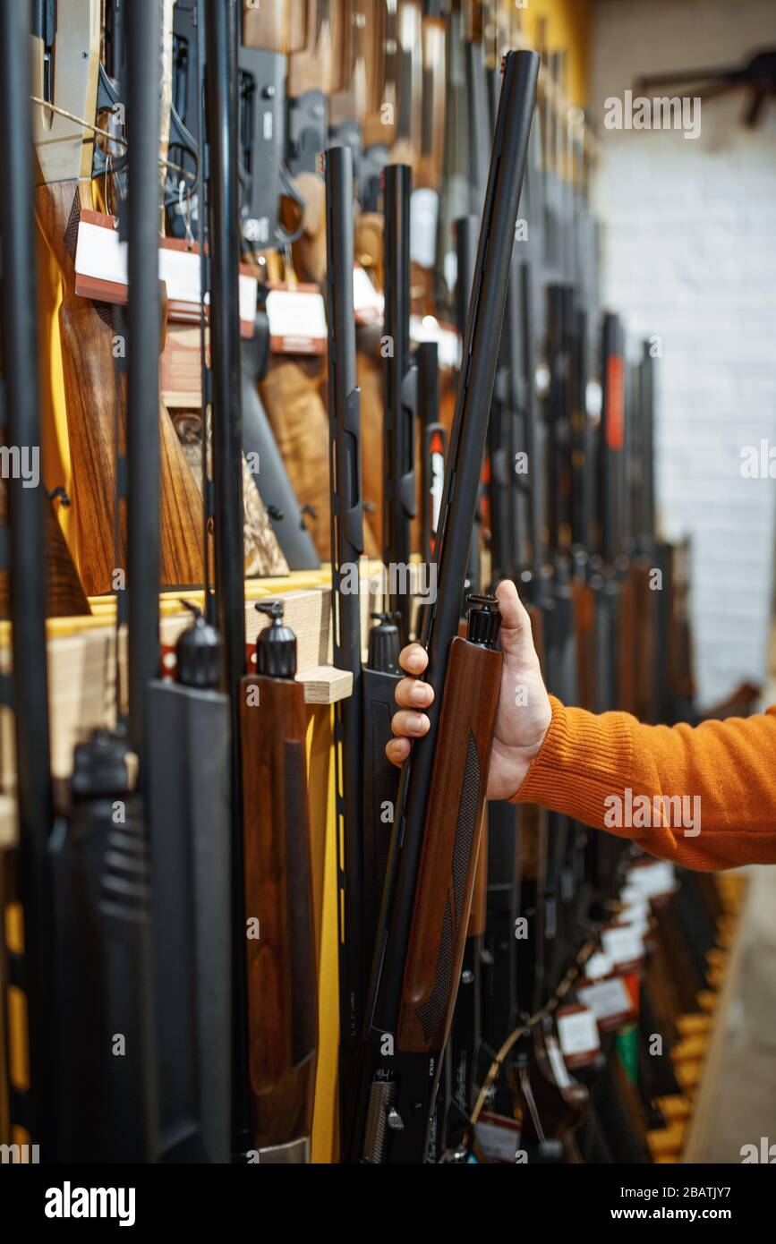 Man choosing rifle at showcase in gun shop Stock Photo - Alamy
