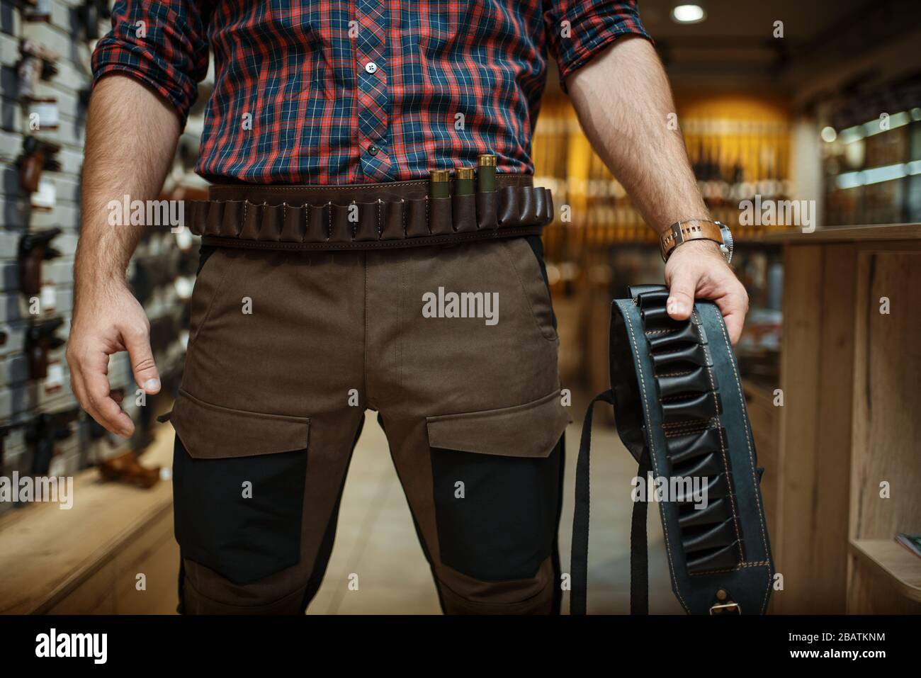 Man in hunting uniform holds ammo belt in gun shop Stock Photo - Alamy