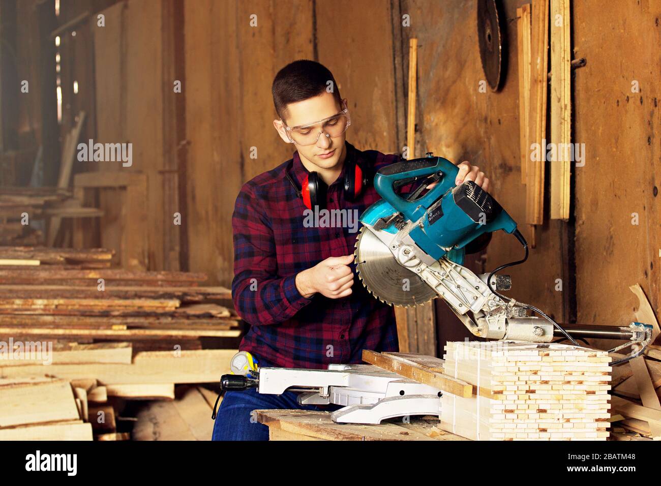 Workman at the sawmill. Young hardworking man Stock Photo - Alamy