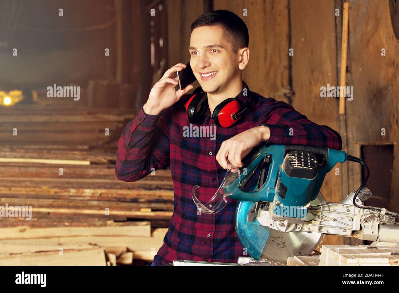 Workman at the sawmill. Young hardworking man Stock Photo - Alamy