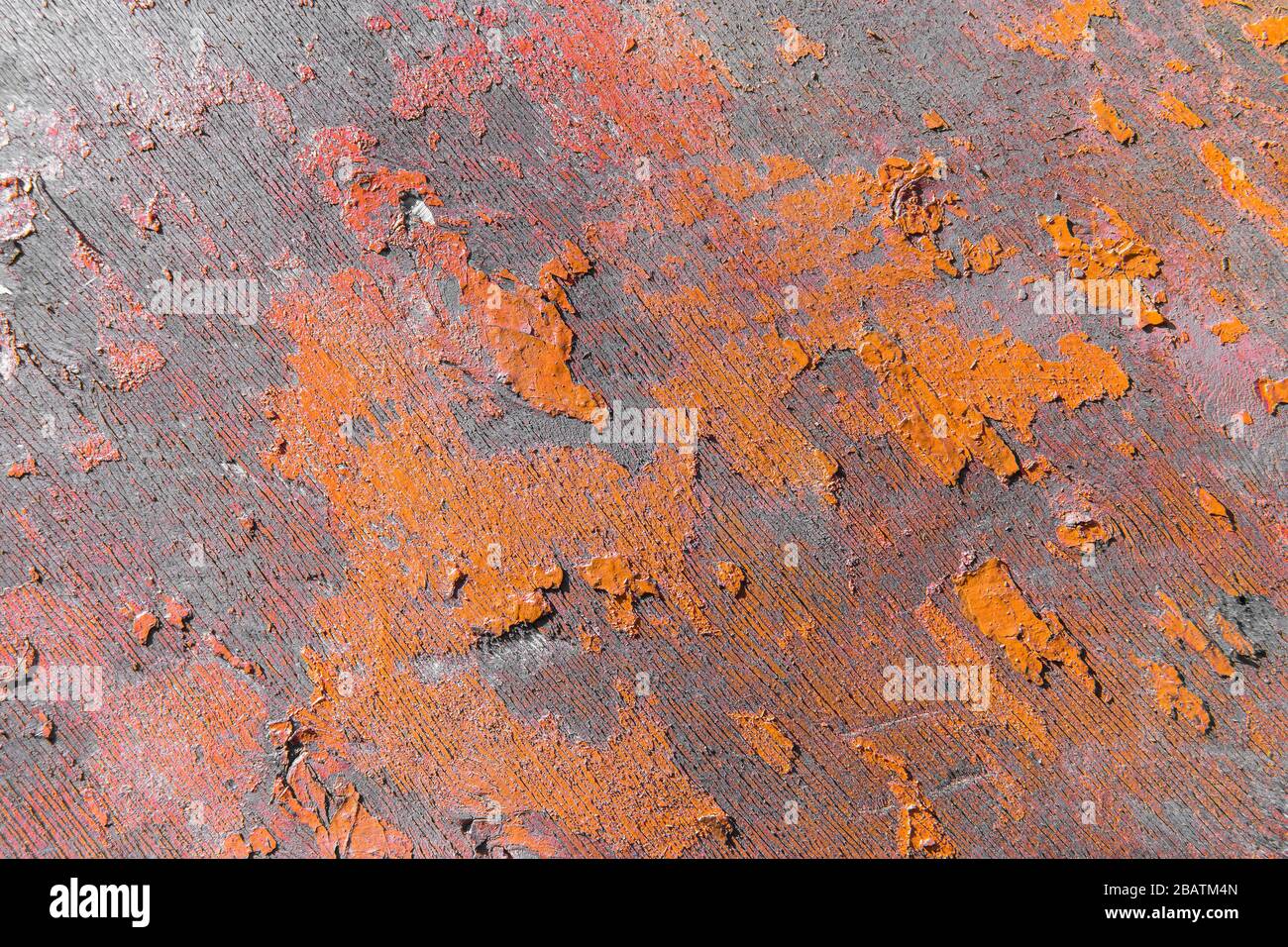 Cracked, chipping red paint on old weathered wooden surface in close up ...