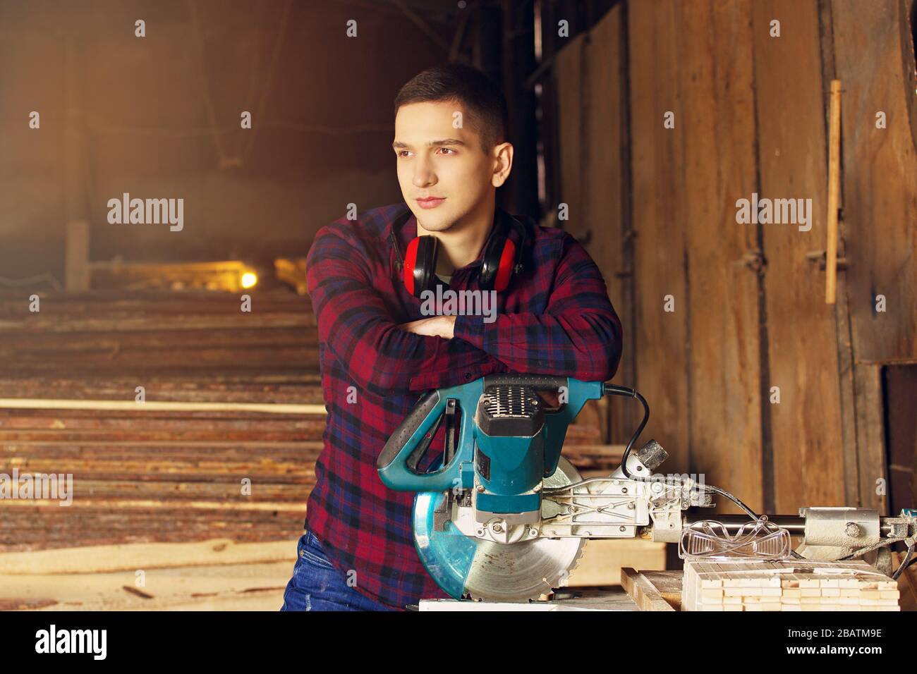 Workman at the sawmill. Young hardworking man Stock Photo - Alamy