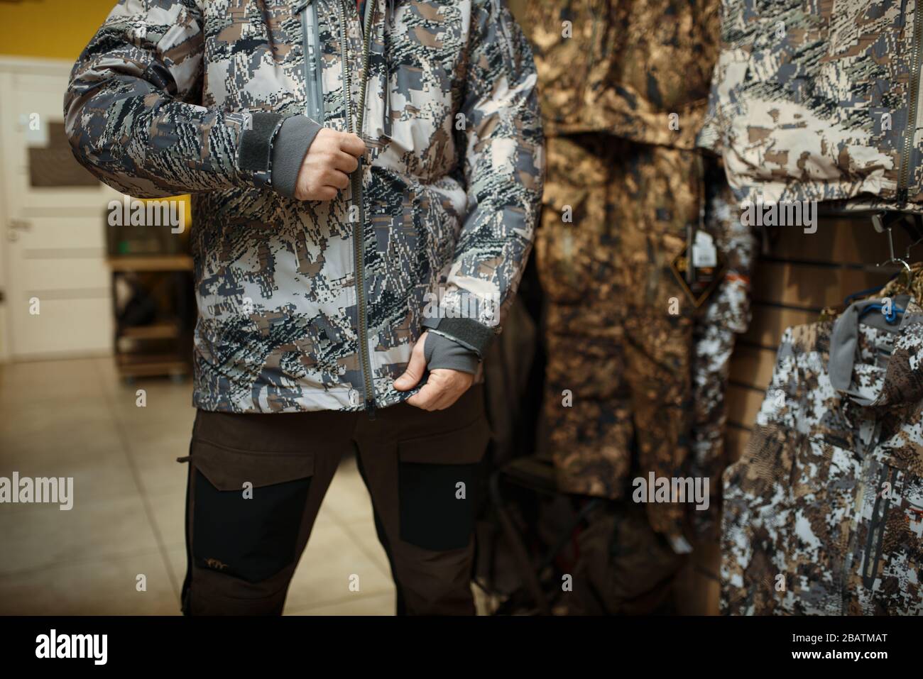 Man trying on uniform at showcase in gun shop Stock Photo - Alamy