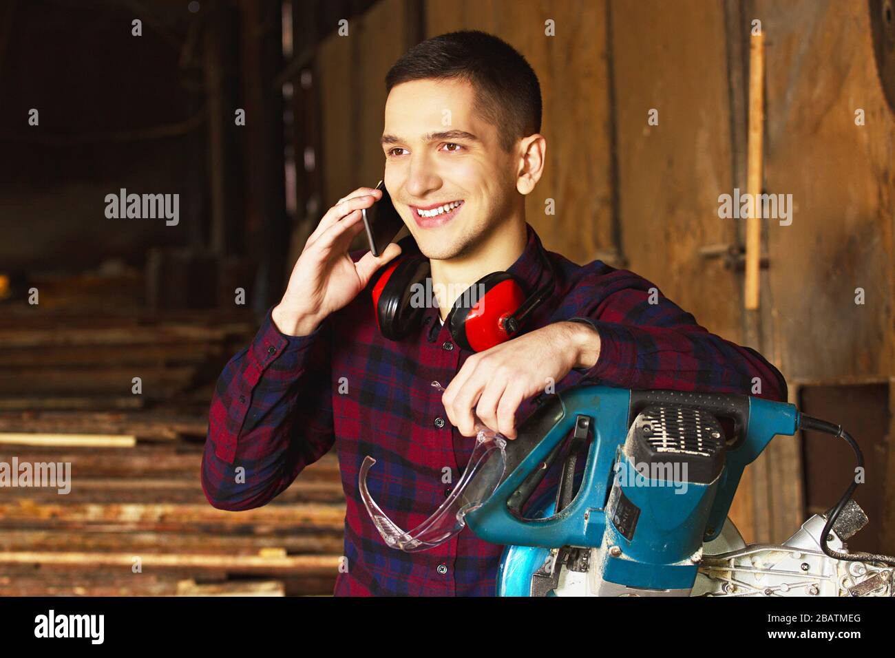 Workman at the sawmill. Young hardworking man Stock Photo - Alamy