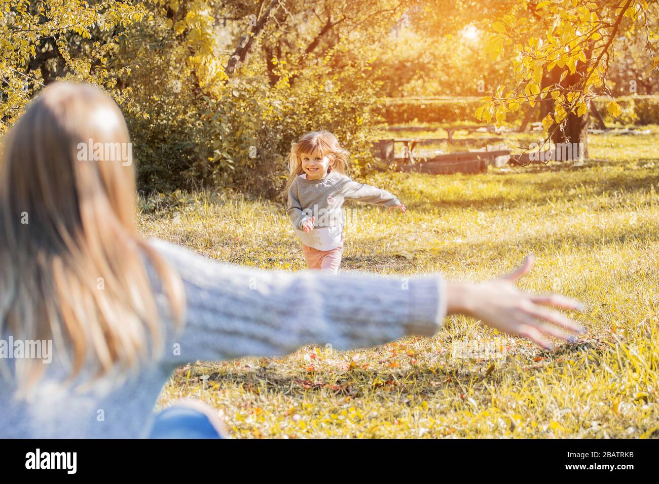 Nice little girl running into her mother's hug and smiling. Daughter ...