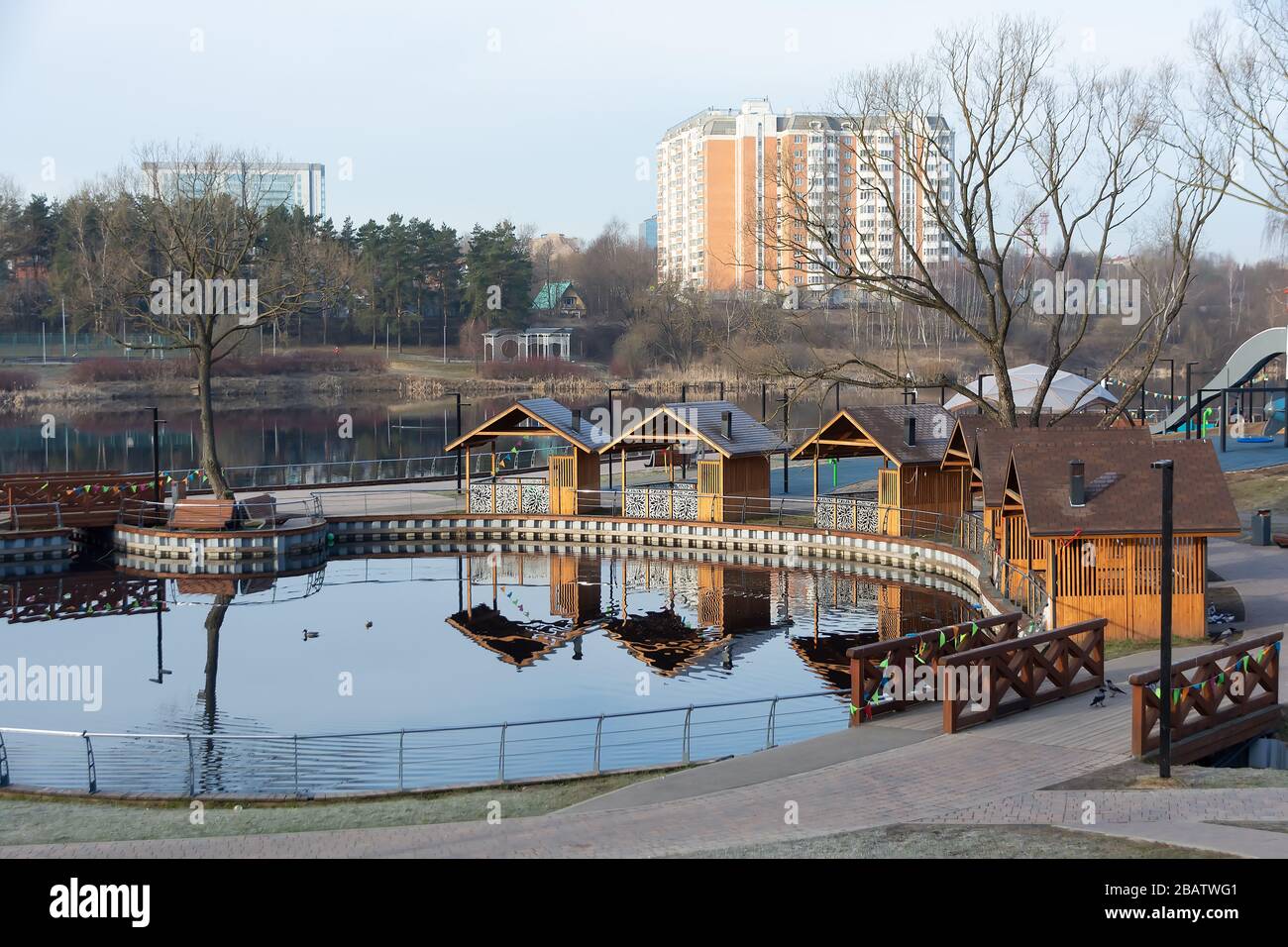 Panorama of small city park with pond, line of pavilions and bridge ...