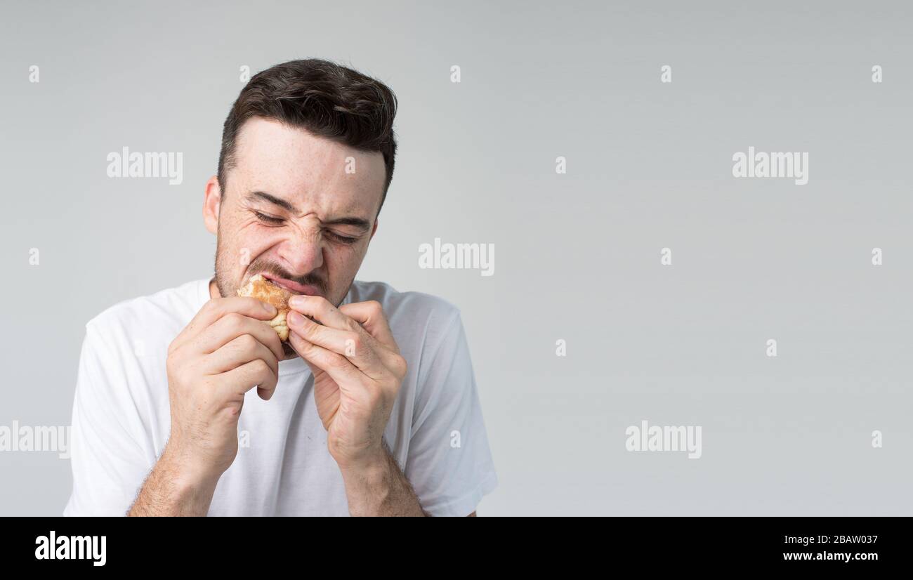 Young man isolated over background.Biting and chewing tasty delicious ...