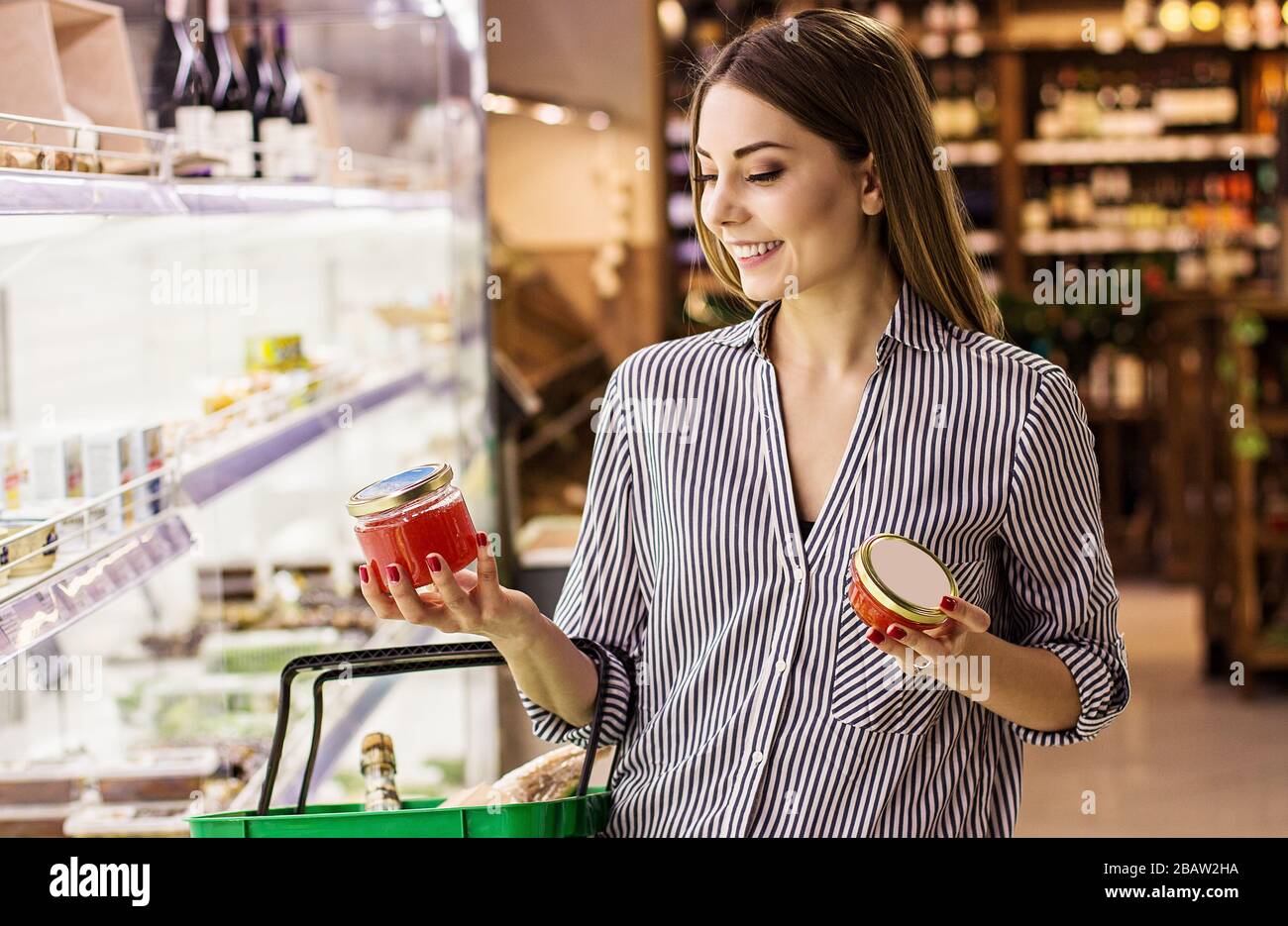 Horizontal shot happy woman reading label with price at caviar jar ...