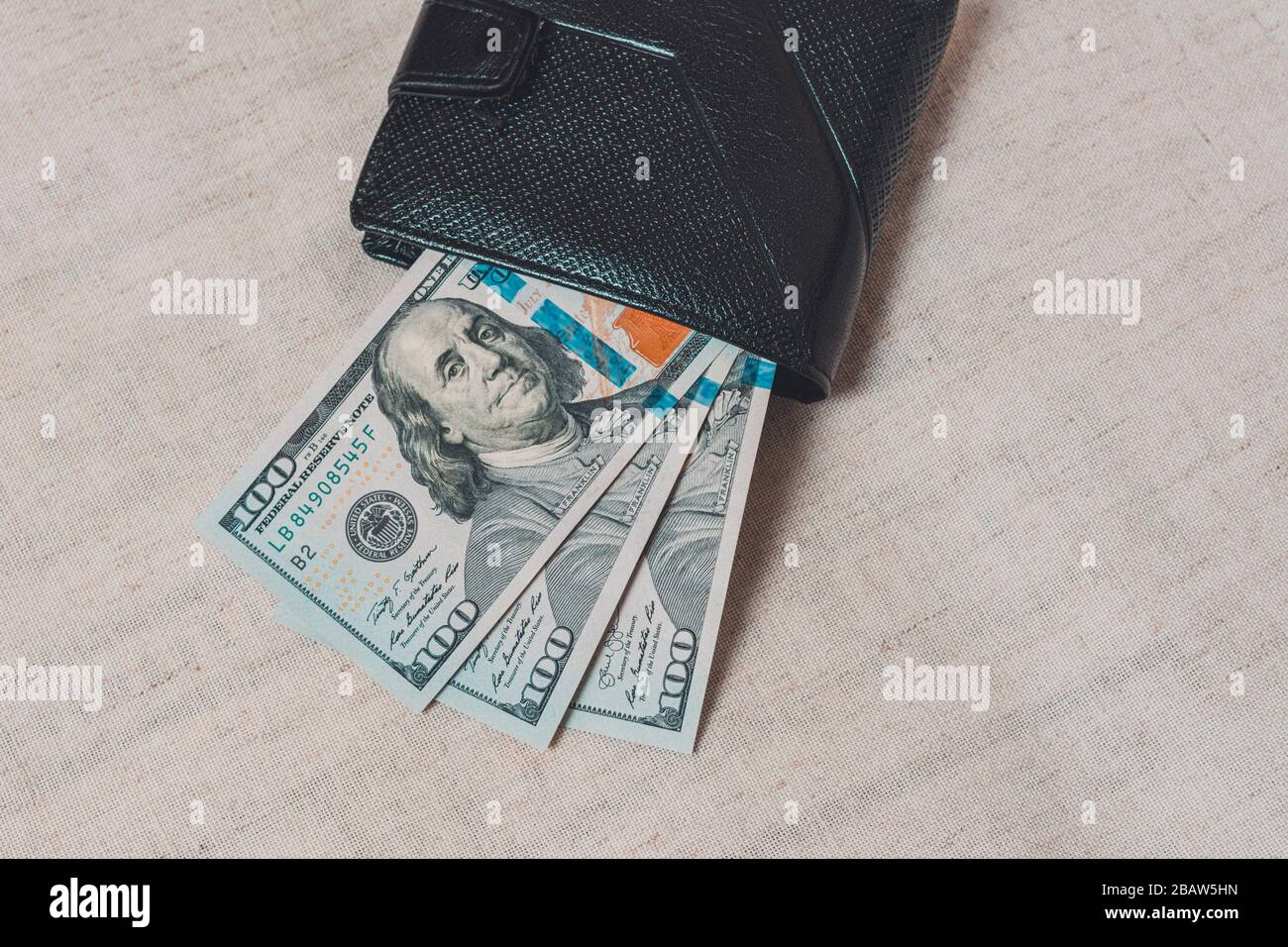 One hundred dollars lie in a black purse on a gray background Stock ...