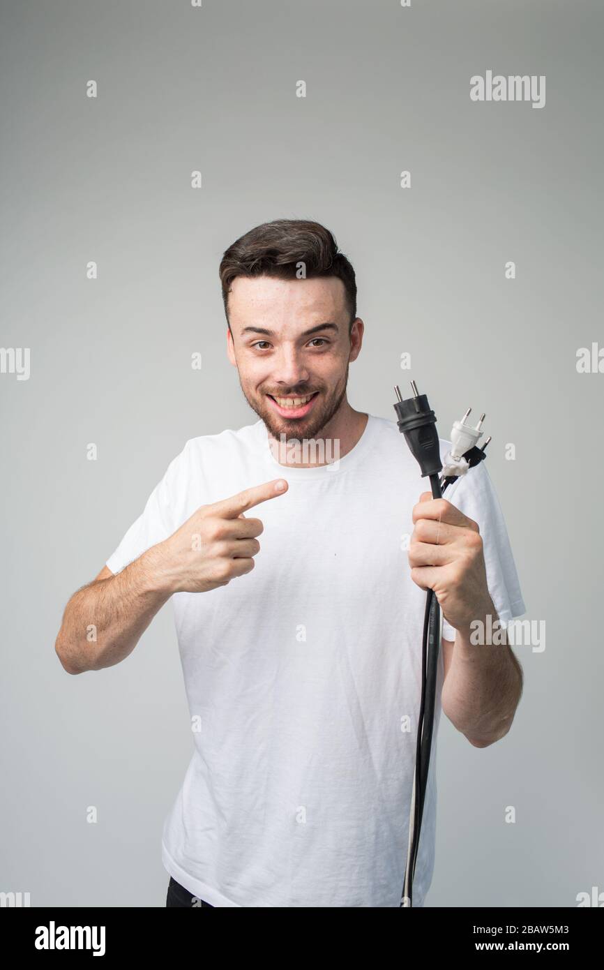 Young man isolated over background. Cheerful positive guy hold cord ...