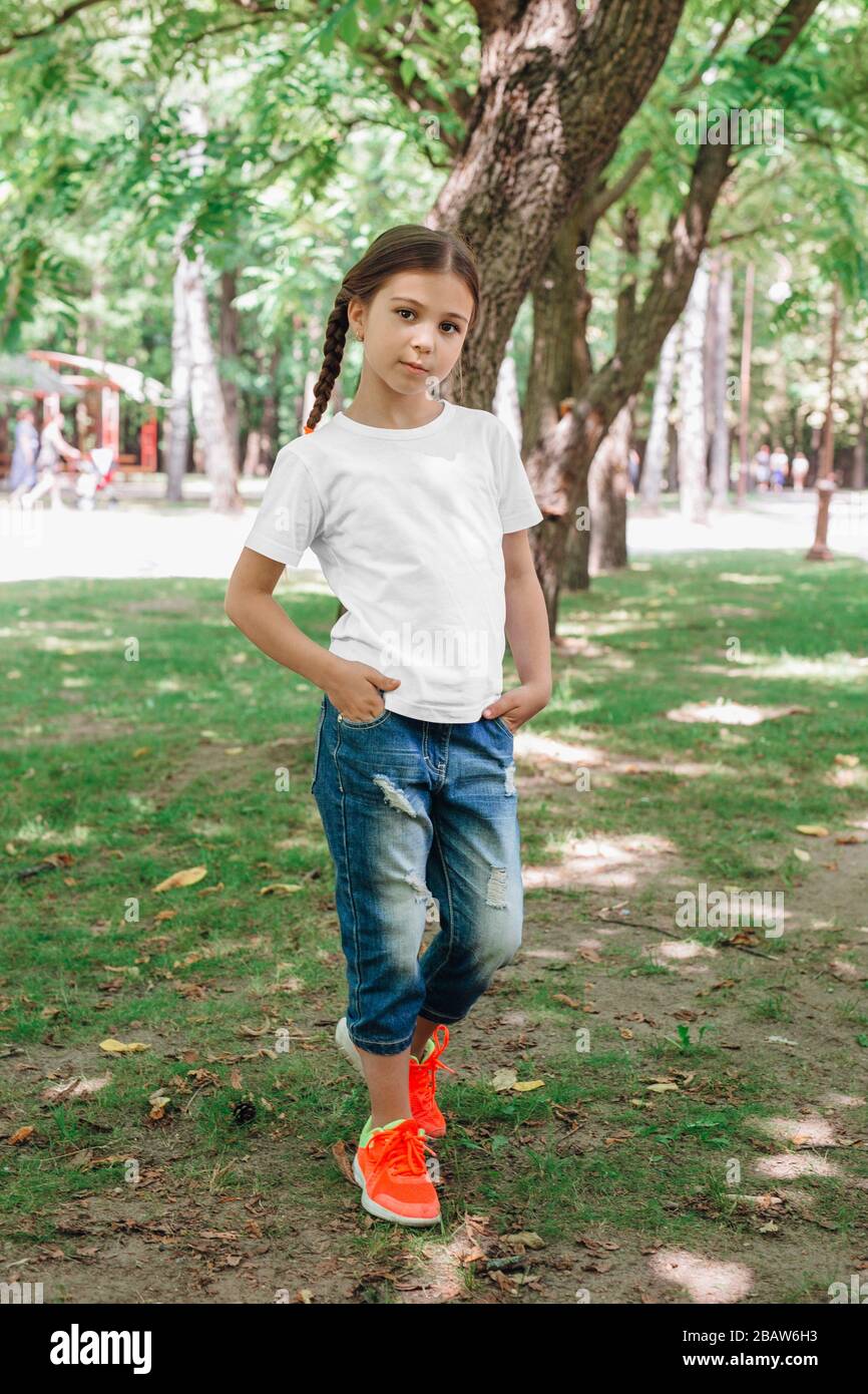 little smiling girl model in white shirt posing in park Stock Photo - Alamy