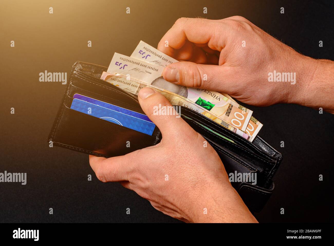 Closeup in the hands of a man's wallet when he pulls out a 500 hryvnia ...