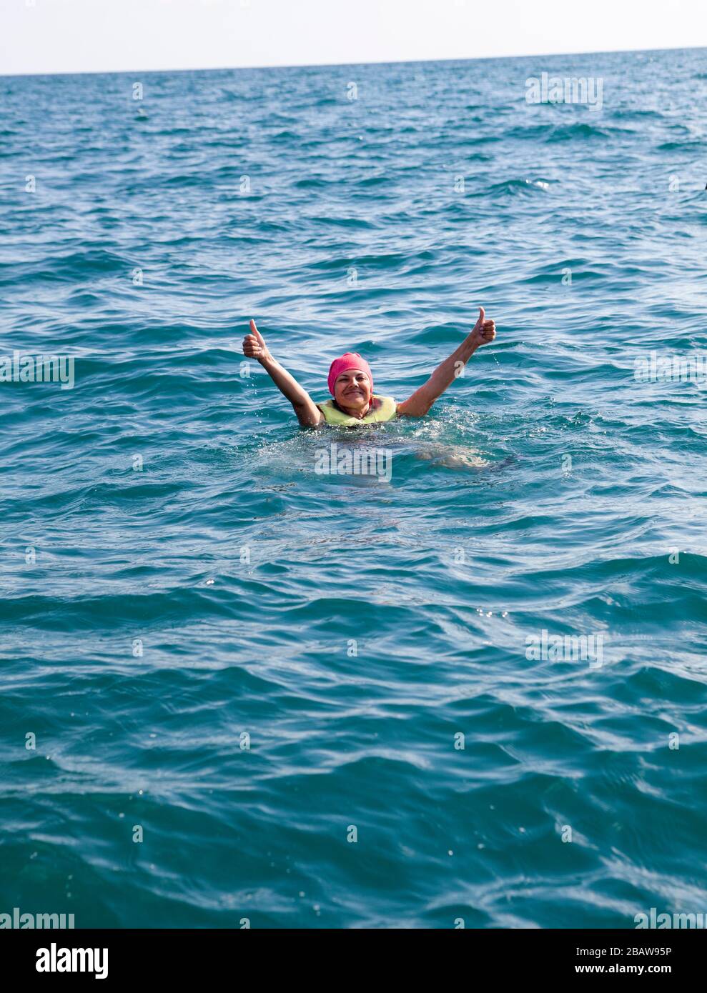 European woman staying afloat with cork lifesaving vest in open ocean ...