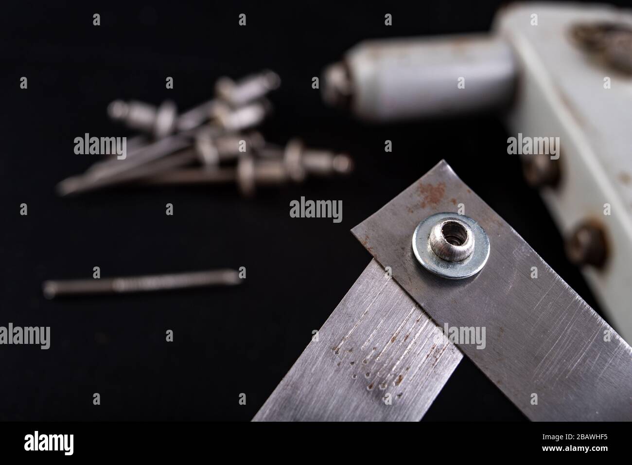 Riveting two pieces of metal sheet. Connecting steel with rivets. Dark ...