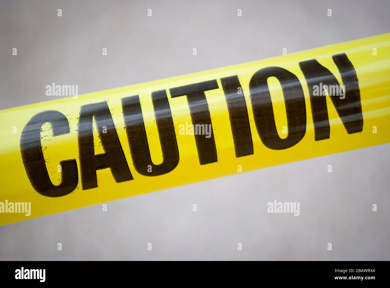 Single word CAUTION in black letters on yellow tape stretched ...