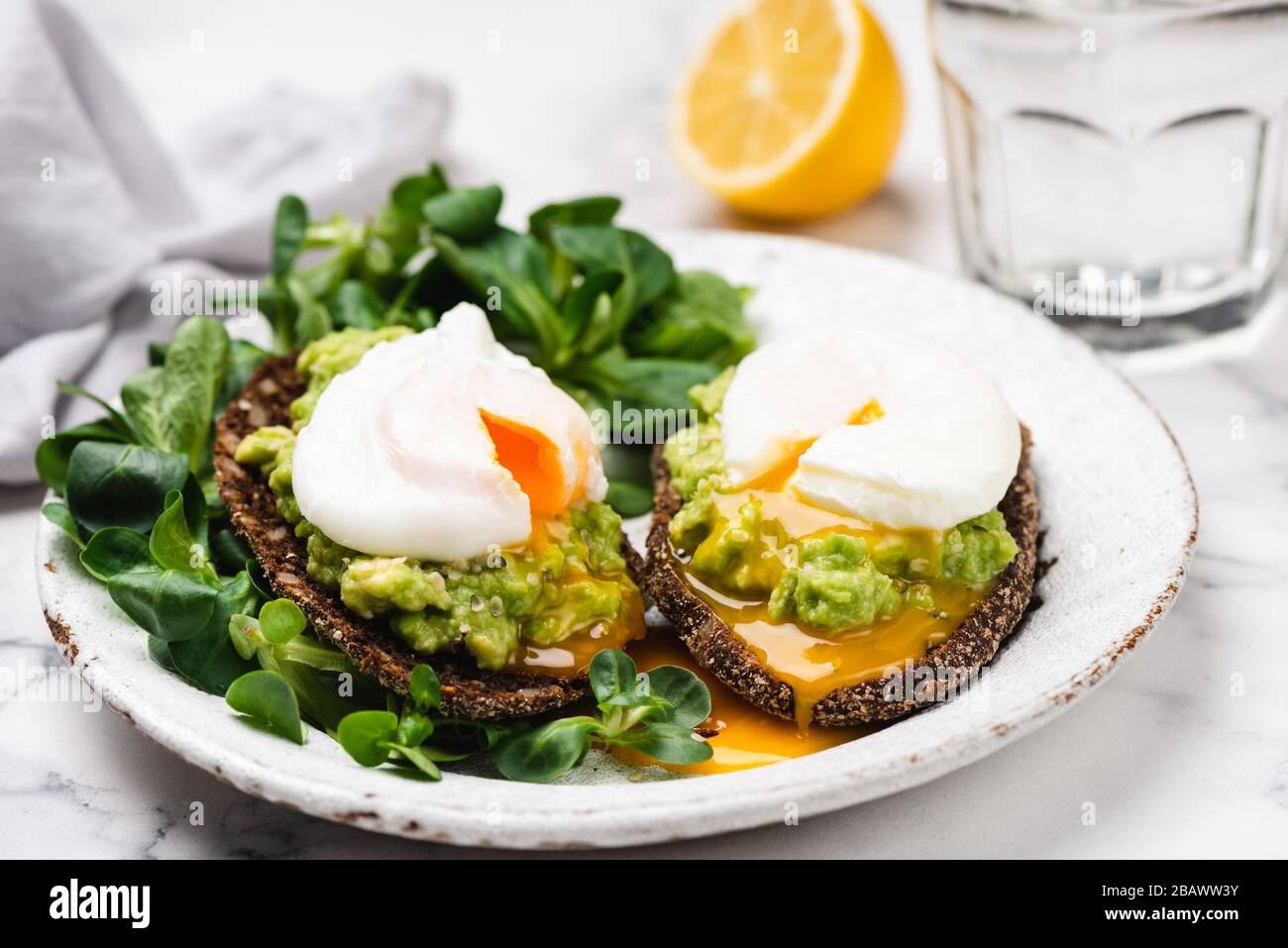 Avocado rye bread toast with poached egg on plate. Healthy appetizer ...