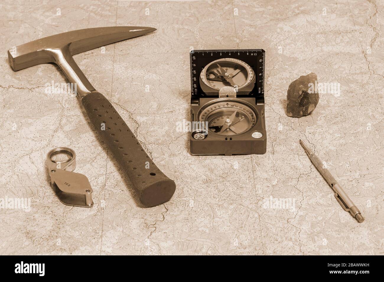 The tools of the geologist laid out on a topographic map. Background ...