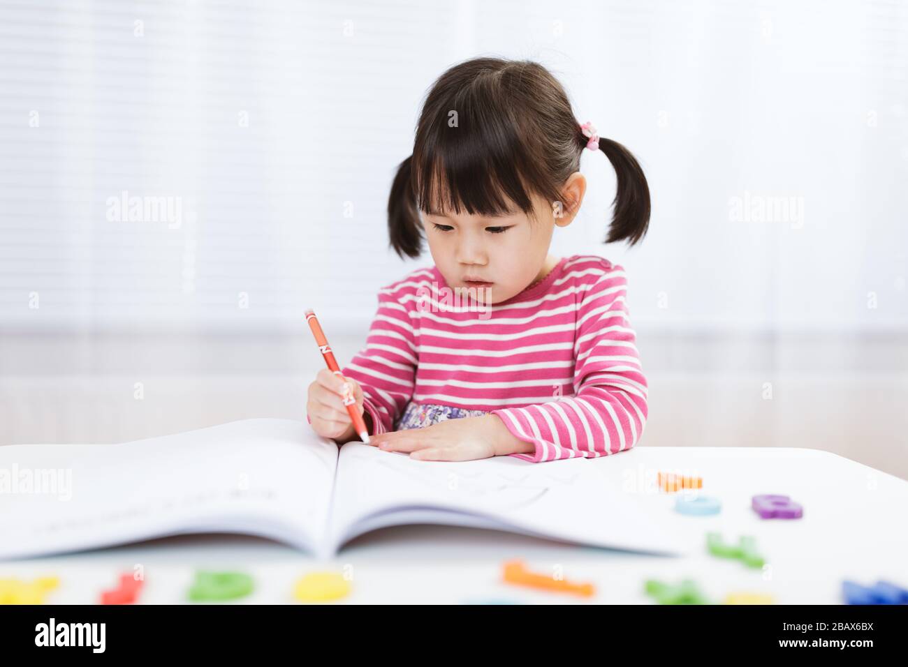 toddler girl practice writing letters for homeschooling Stock Photo - Alamy