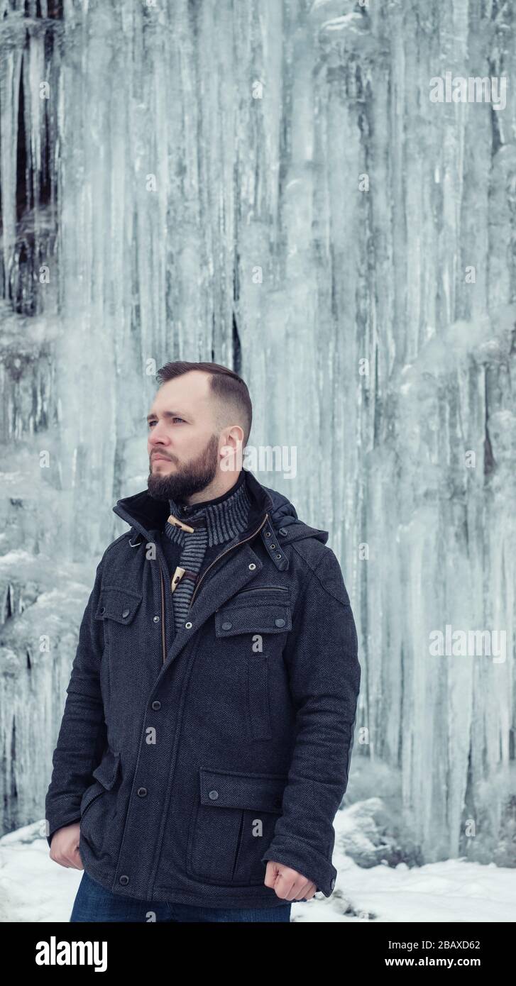 Man standing against cliff full of icicles Stock Photo - Alamy