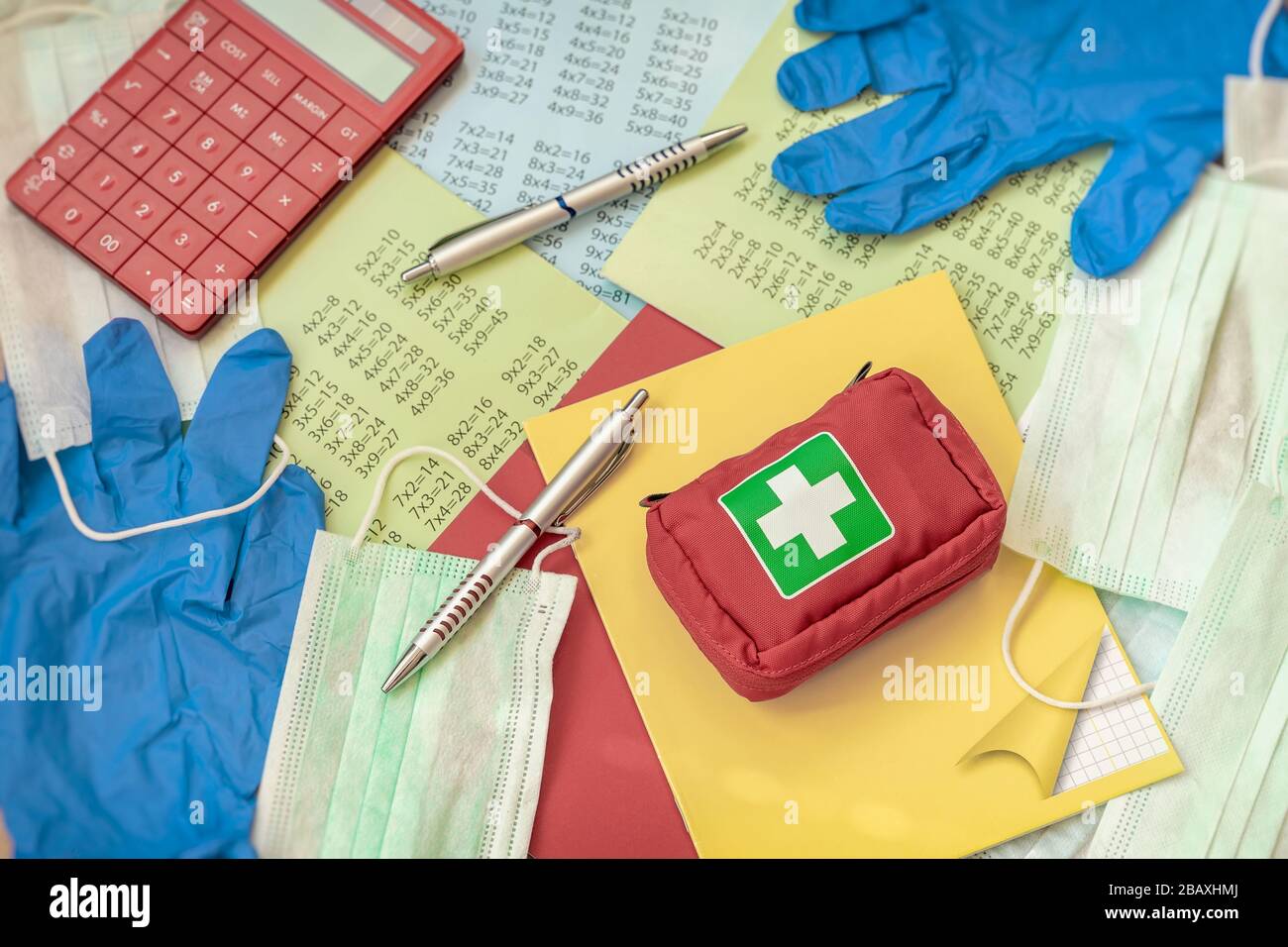 Calculator, pens, medical masks and first aid kit on a school notebook ...