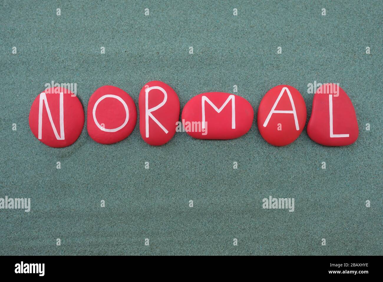 Normal word composed with red colored stone letters over green sand ...