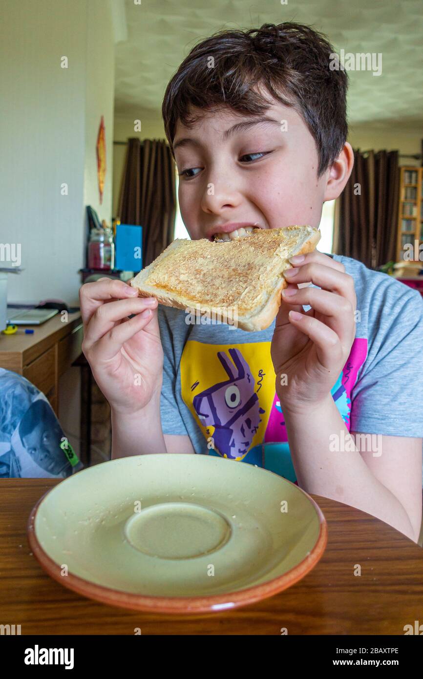 A young boy eating a slice of buttered toast Stock Photo - Alamy