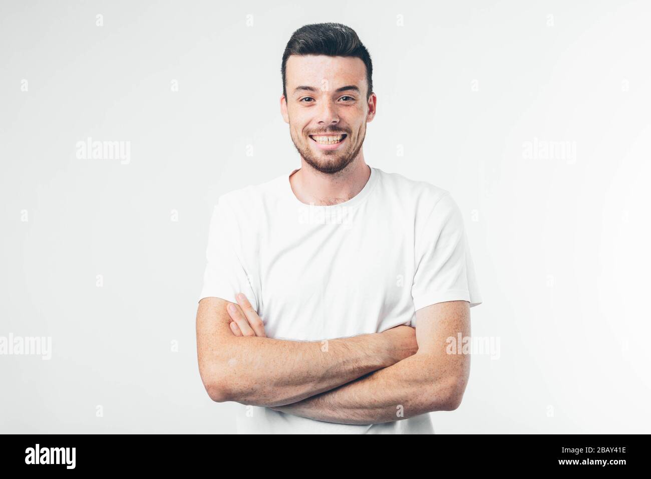 Young brunette man with beard dressed in white T-shirt. Guy confident ...