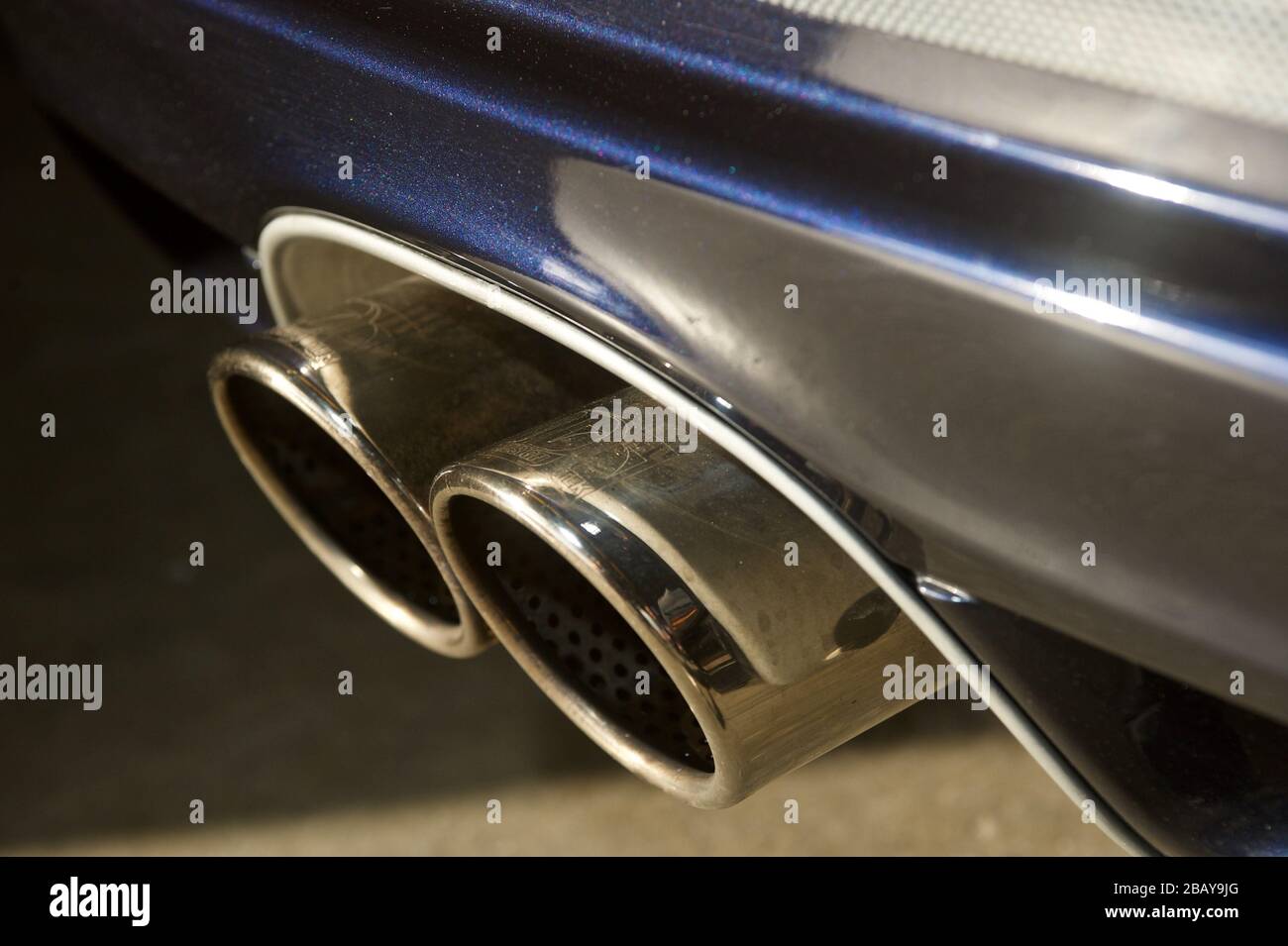 Twin exhaust tailpipes, stainless steel, on blue car Stock Photo - Alamy