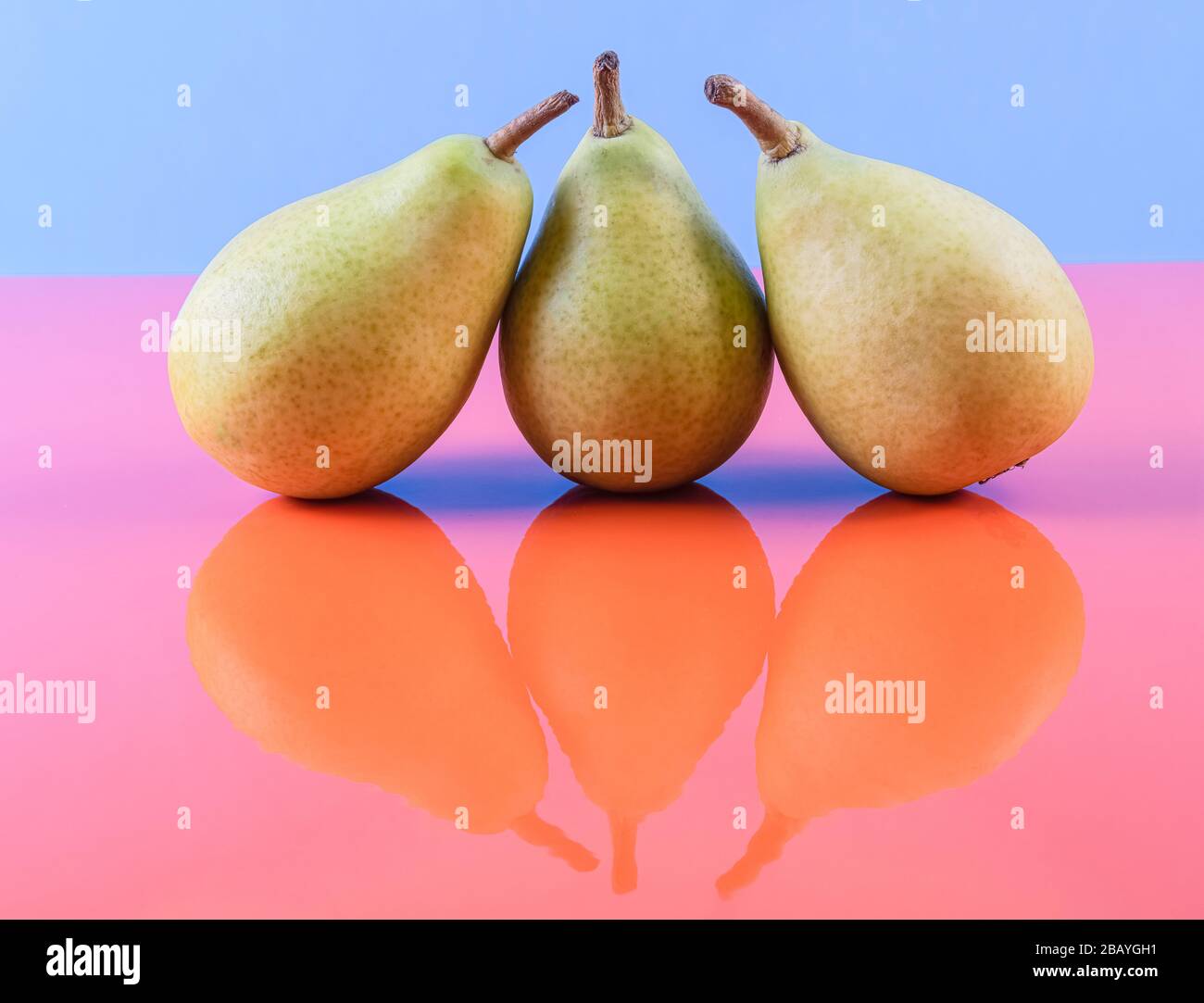 Close-up of three tasty looking pears on a reflective surface on a ...