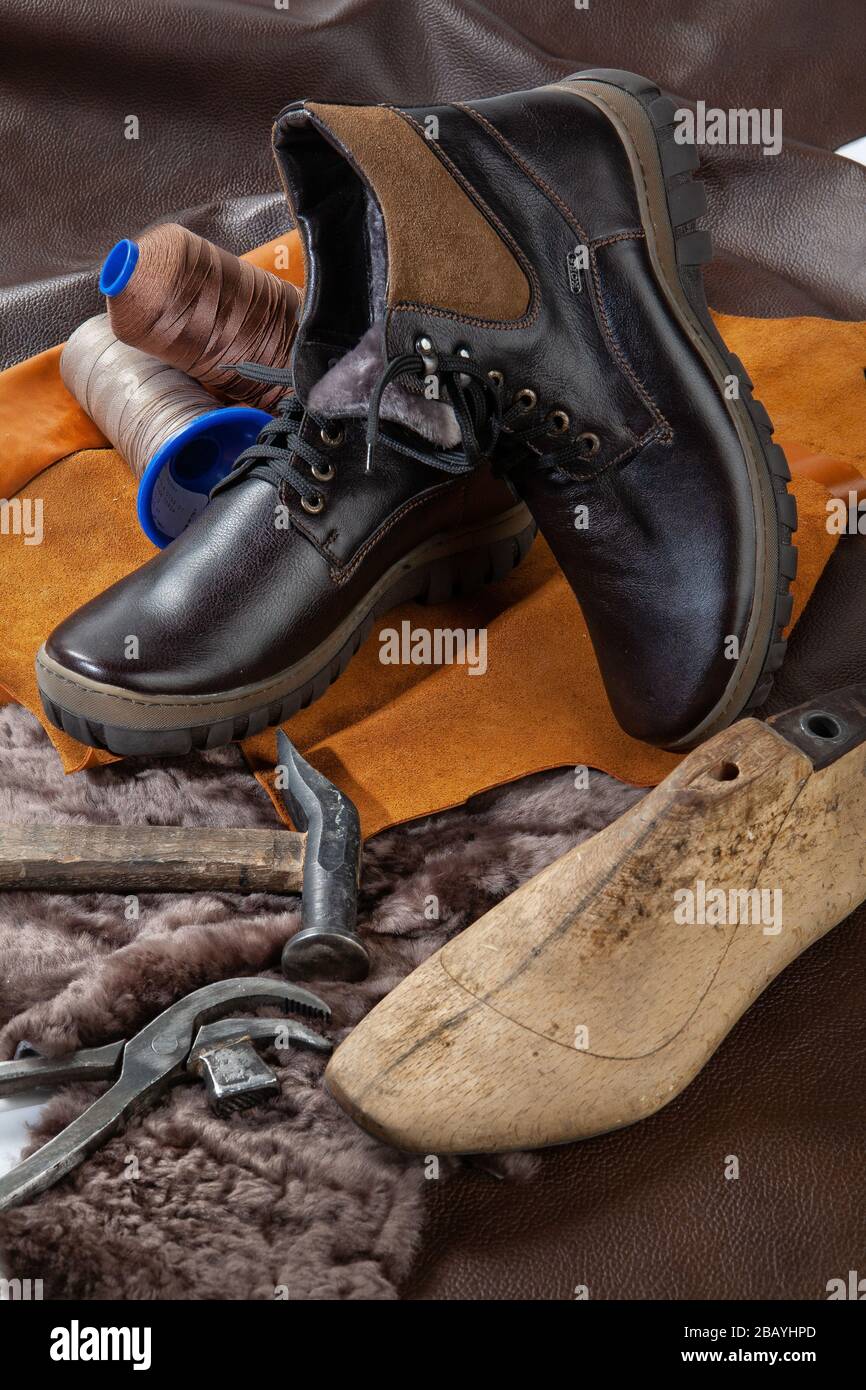Shoes, shoemaking tools and pieces of leather on a studio background ...