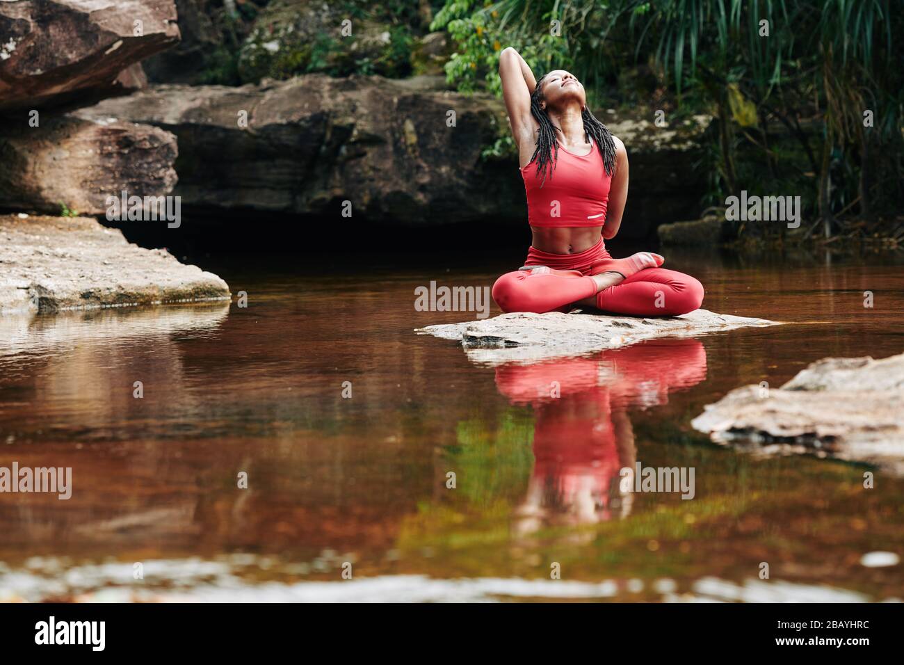 Pretty fit young woman doing one arm up, one arm behind yoga clasp when ...